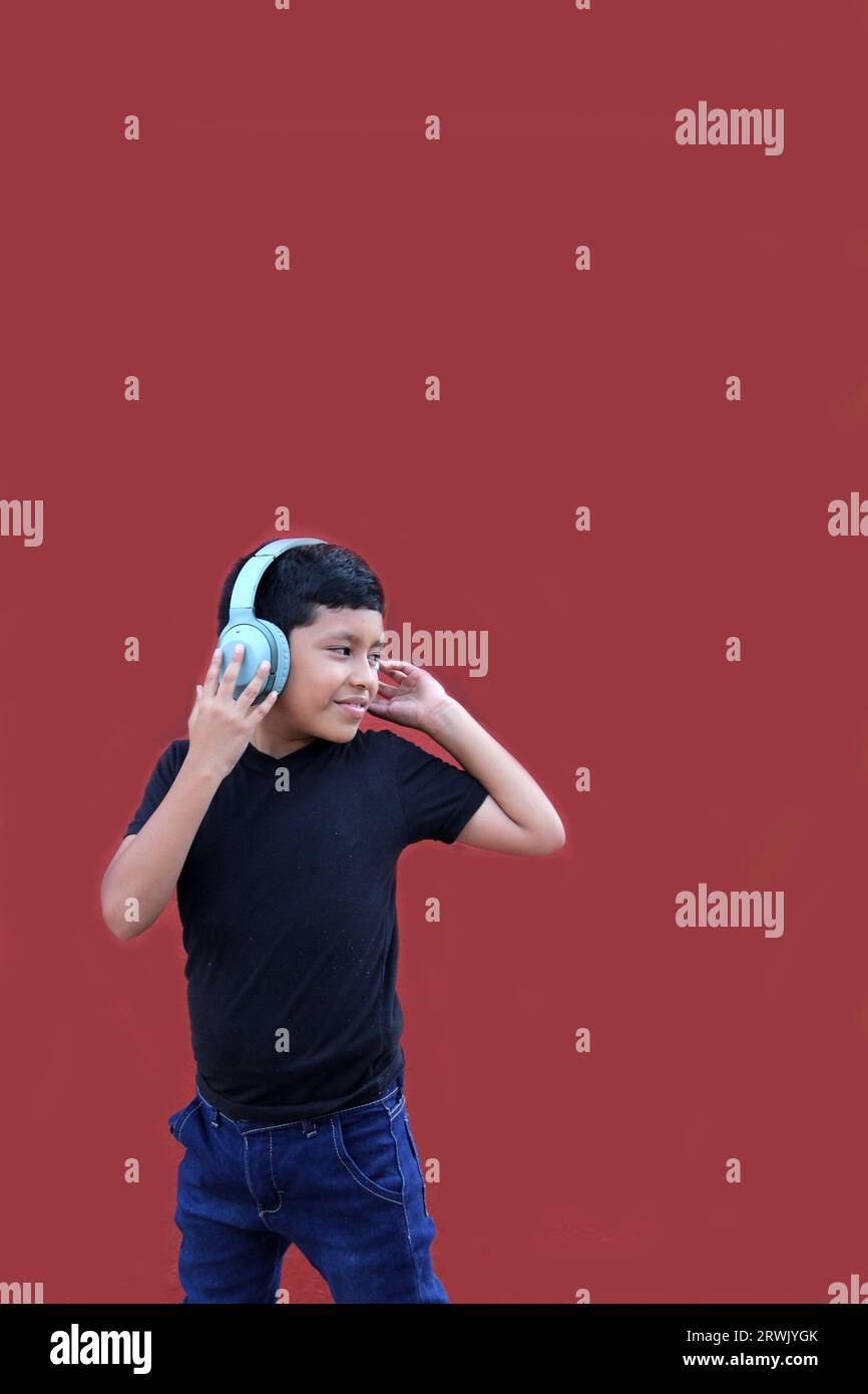 9-year-old dark-skinned Latino boy listens to his headphones and enjoys ...