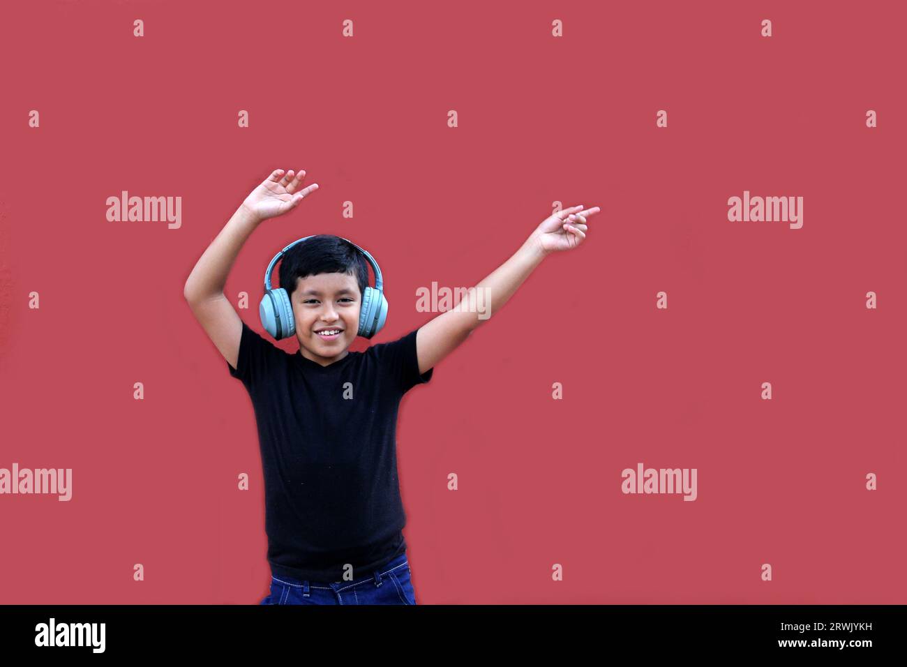 9-year-old dark-skinned Latino boy listens to his headphones and enjoys ...