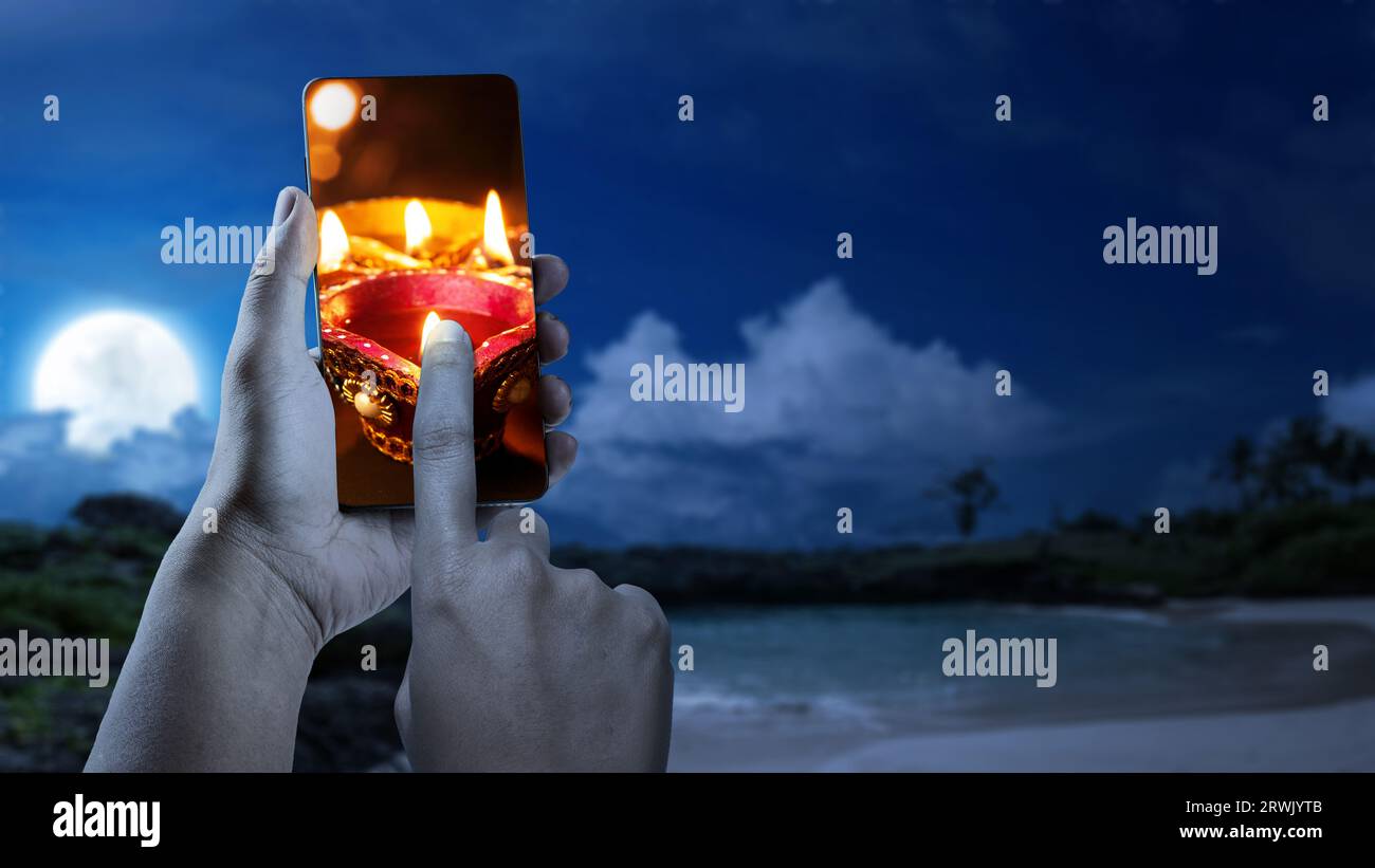 Human hand showing Diya oil lamps for the Diwali festival on the mobile ...