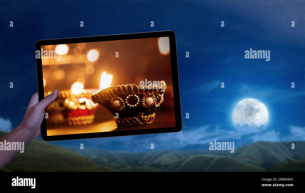 Human hand showing Diya oil lamps for the Diwali festival on the tablet ...