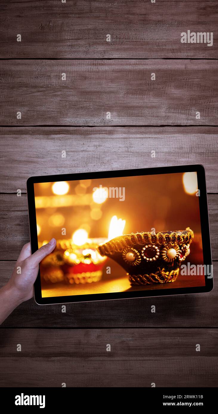 Human hand showing Diya oil lamps for the Diwali festival on the tablet ...