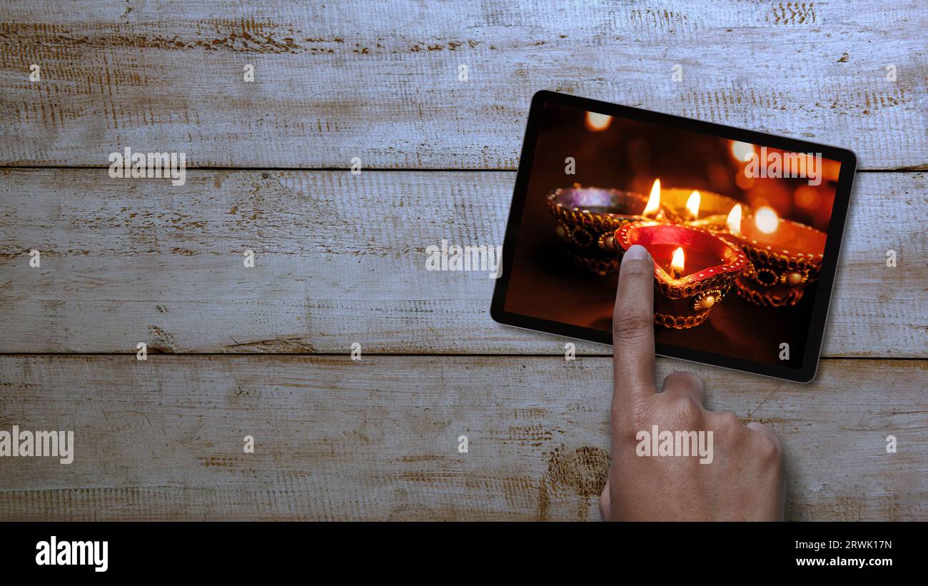 Human hand showing Diya oil lamps for the Diwali festival on the tablet ...