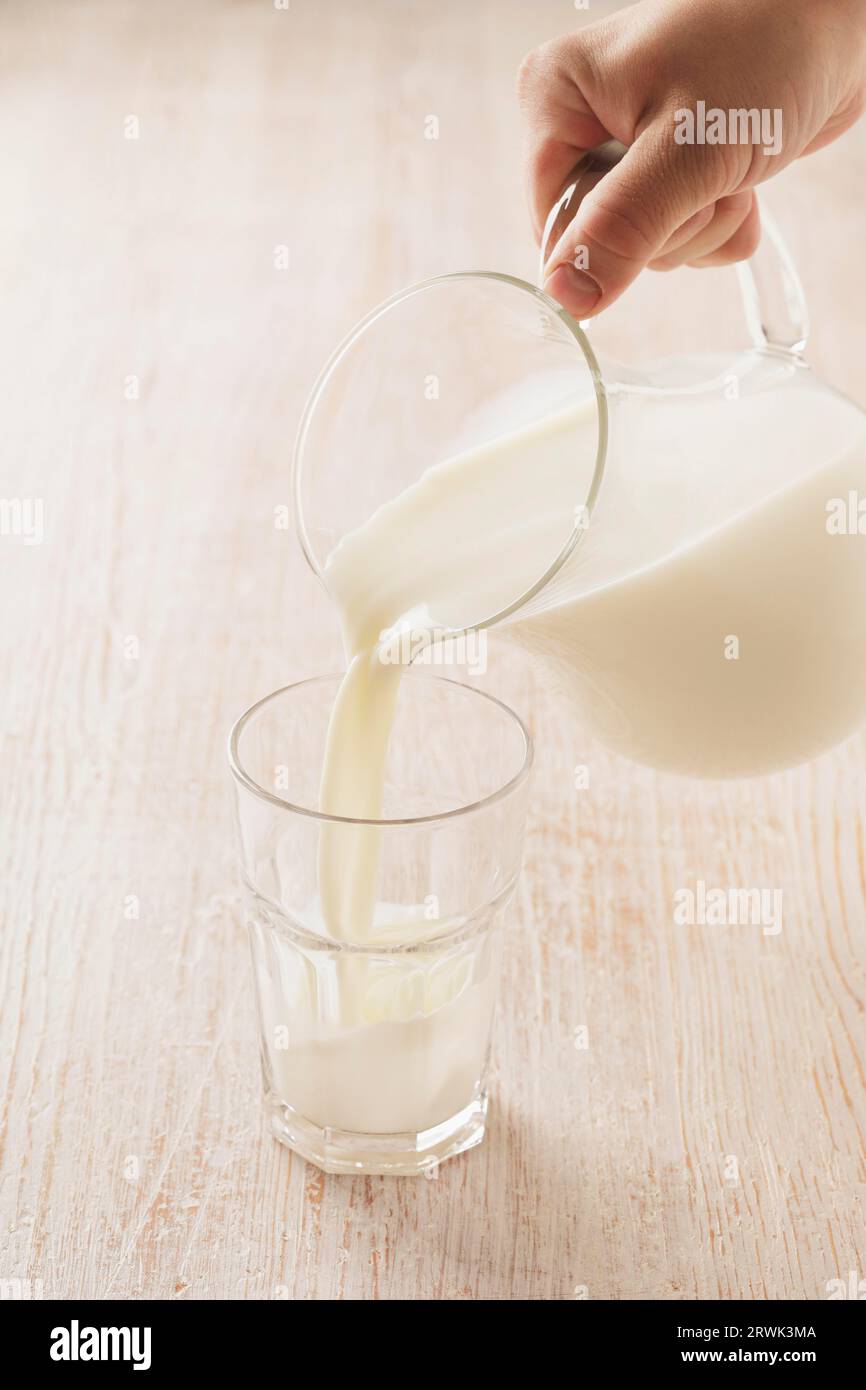 Milk being poured from a pitcher to a glass Stock Photo - Alamy