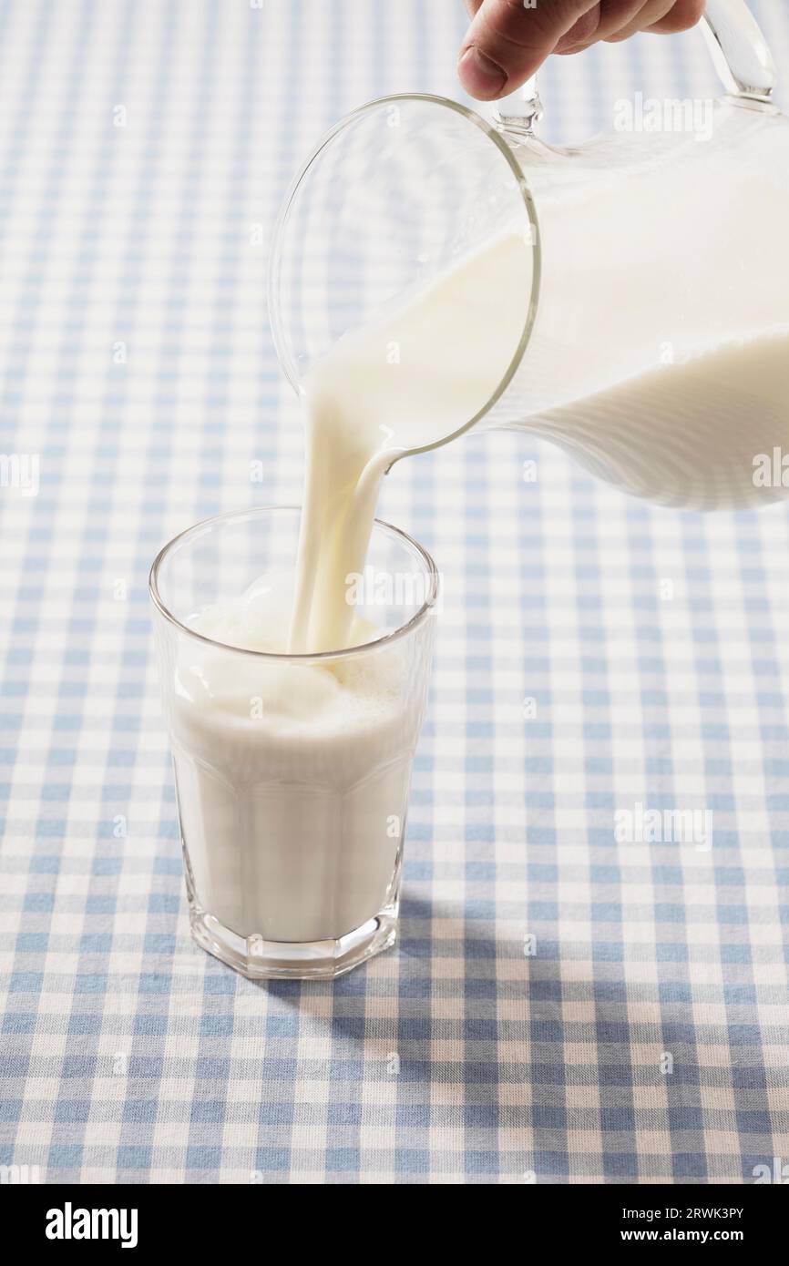 Milk poured from a pitcher to a glass Stock Photo - Alamy