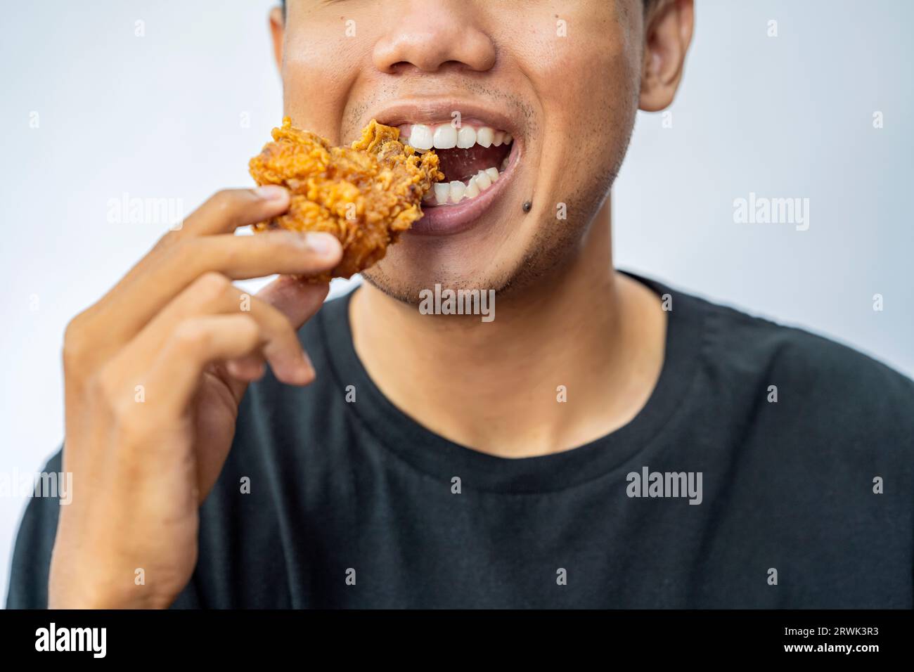 Man eating fried chicken with a white background Stock Photo - Alamy