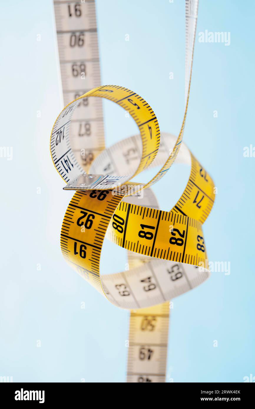 Tangled yellow and white metric tape measure Stock Photo - Alamy