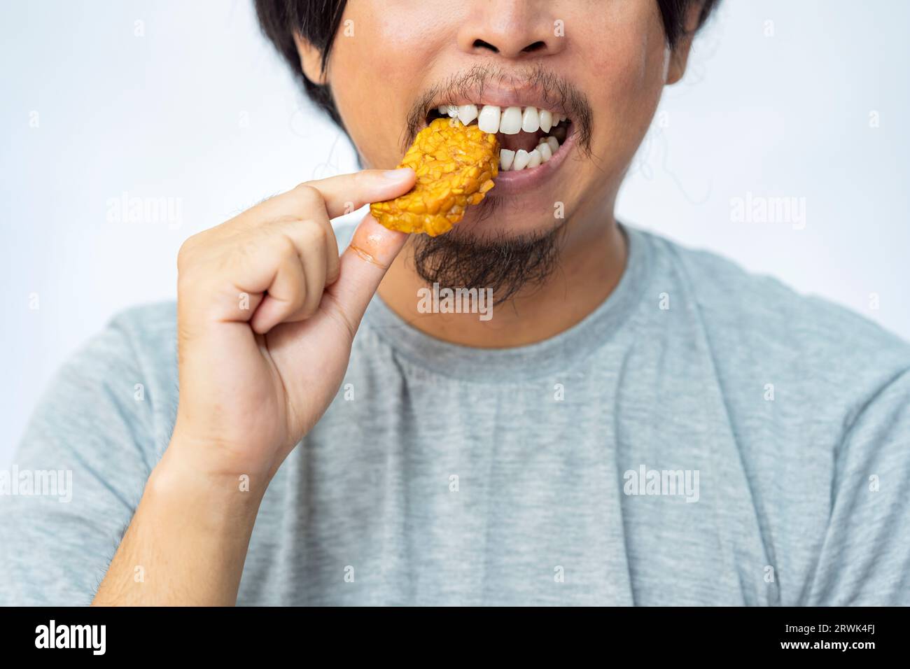Man eating fried tempe with a white background. Traditional Indonesia ...