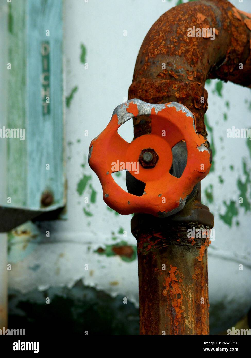Pipe with red tap, in the background light-coloured container with the ...