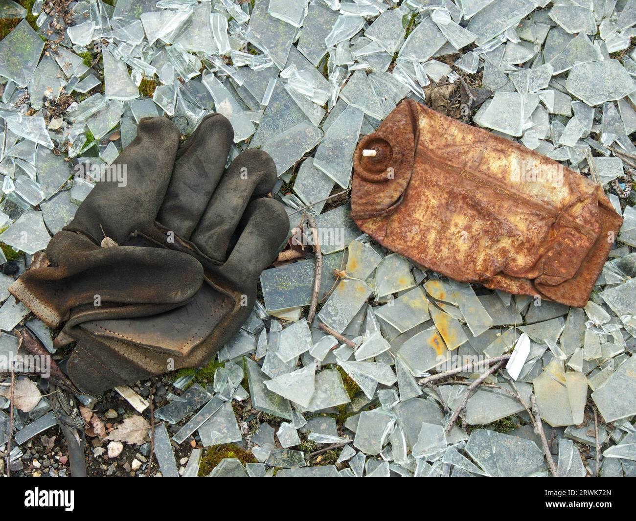 A worn-out leather glove and a rusty spray can, draped on a pile of ...