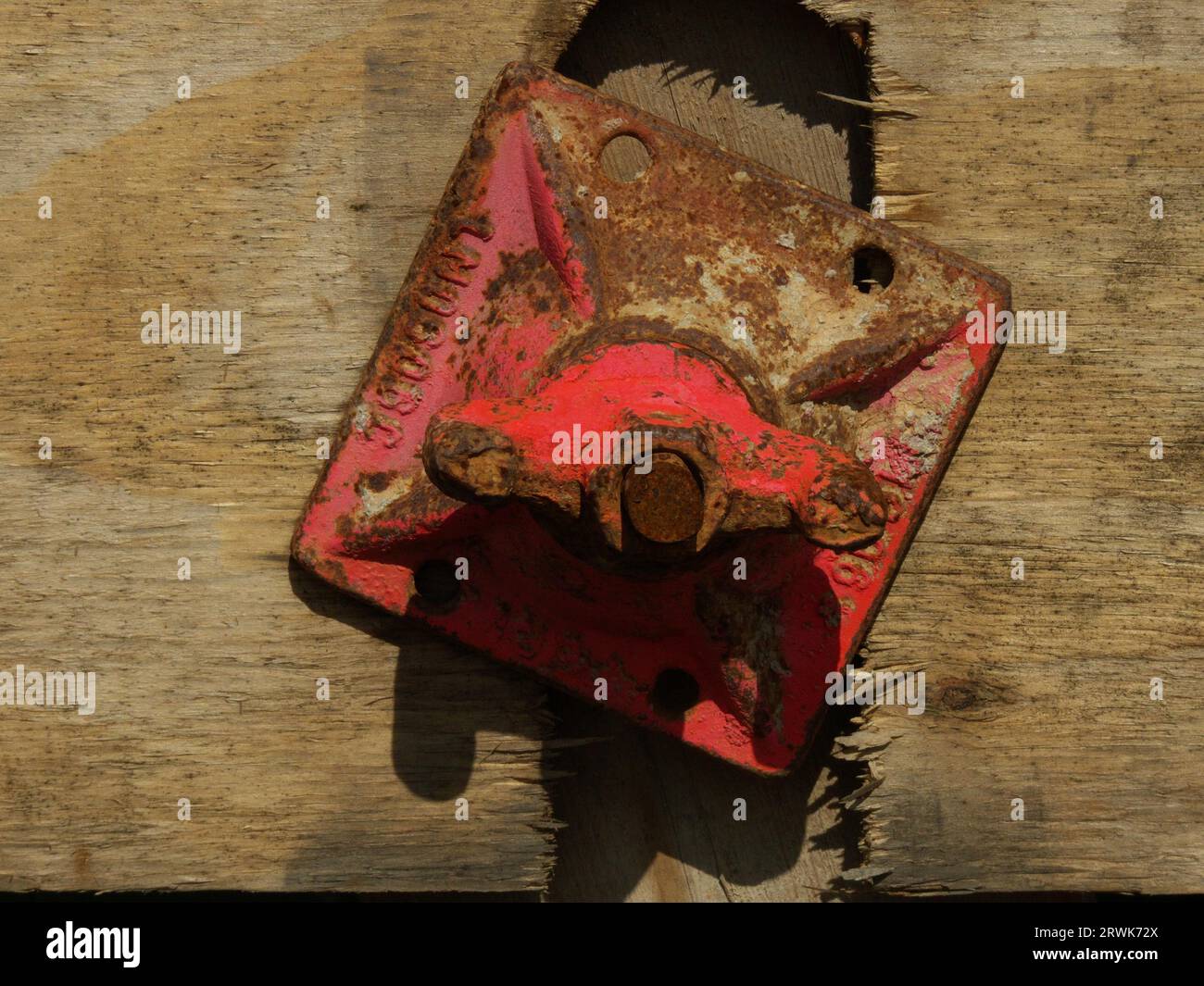 Iron tie rod painted red, slightly rusted, attached to a wooden wall ...