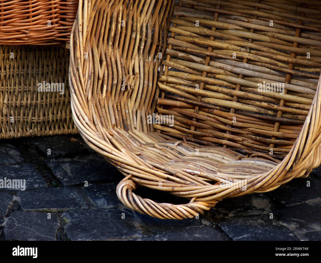 Three woven baskets in different colours spread out on the pavement ...