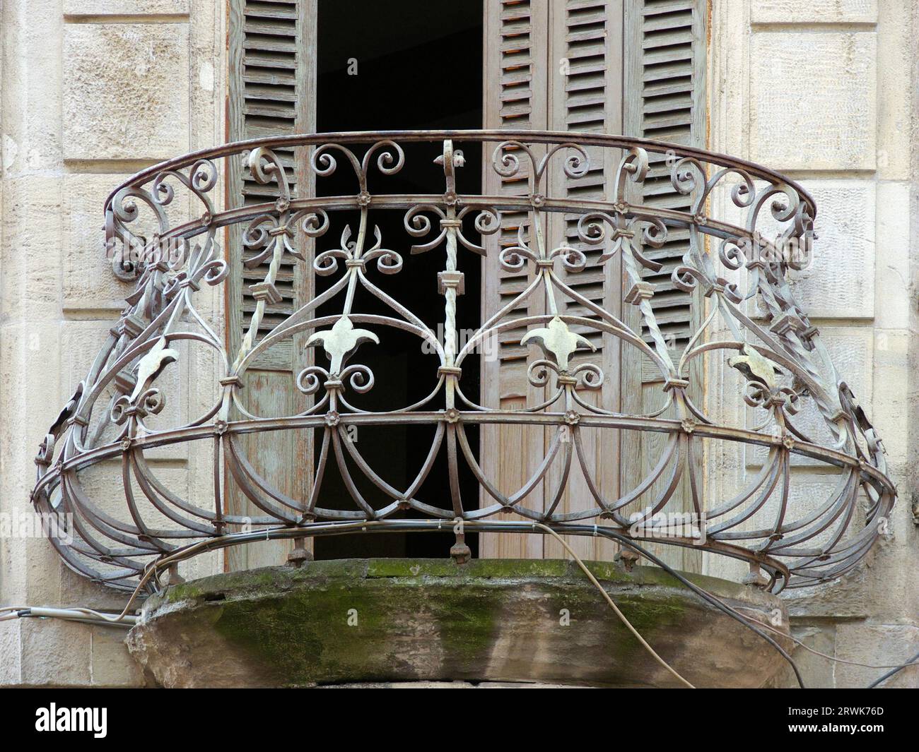 Iron balcony railing on a house front with wooden shutters, detail ...
