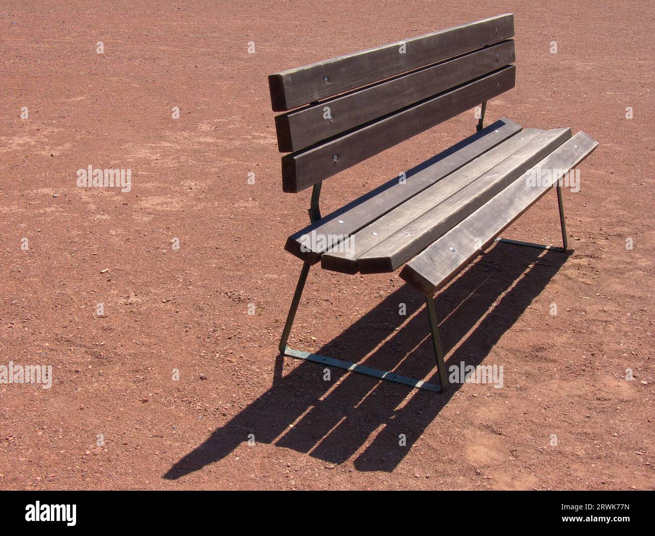 Wooden bench on an empty sports field with red sand, detail Stock Photo ...