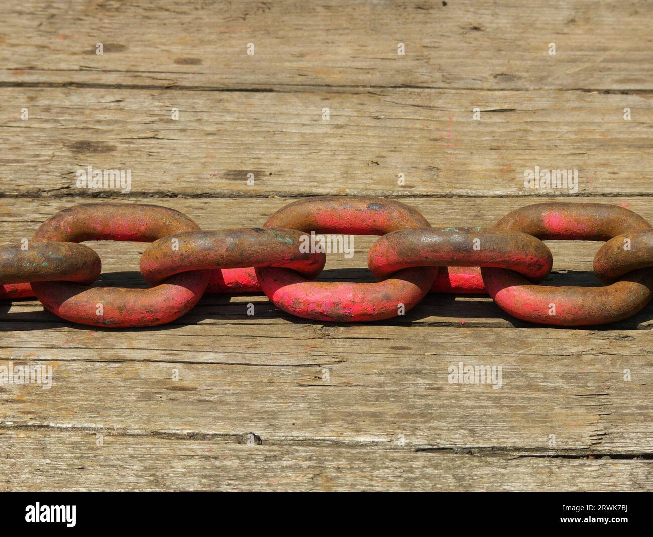 Pink painted chain links of an industrial chain, background wooden ...