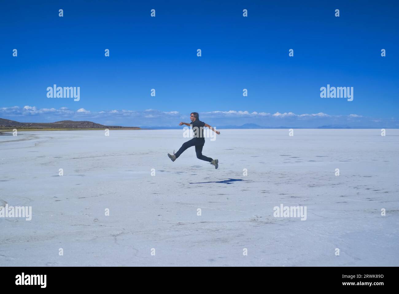 Young man jumps on vast salt plane Salar de Uyuni in Bolivia Stock ...