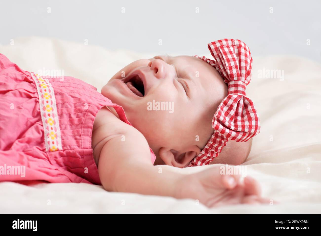 Crying ten weeks old baby girl on bed Stock Photo - Alamy