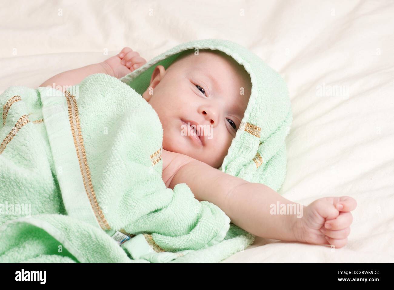 Ten weeks old cute little baby girl toddler wrapped in towel stretching ...