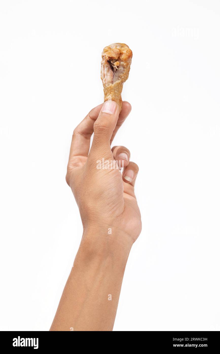 A human hand holding a grilled chicken wing with a white background ...