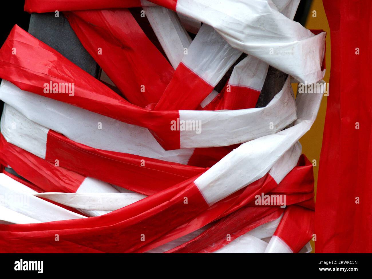 Red and white plastic barrier tape wrapped around a post Stock Photo ...