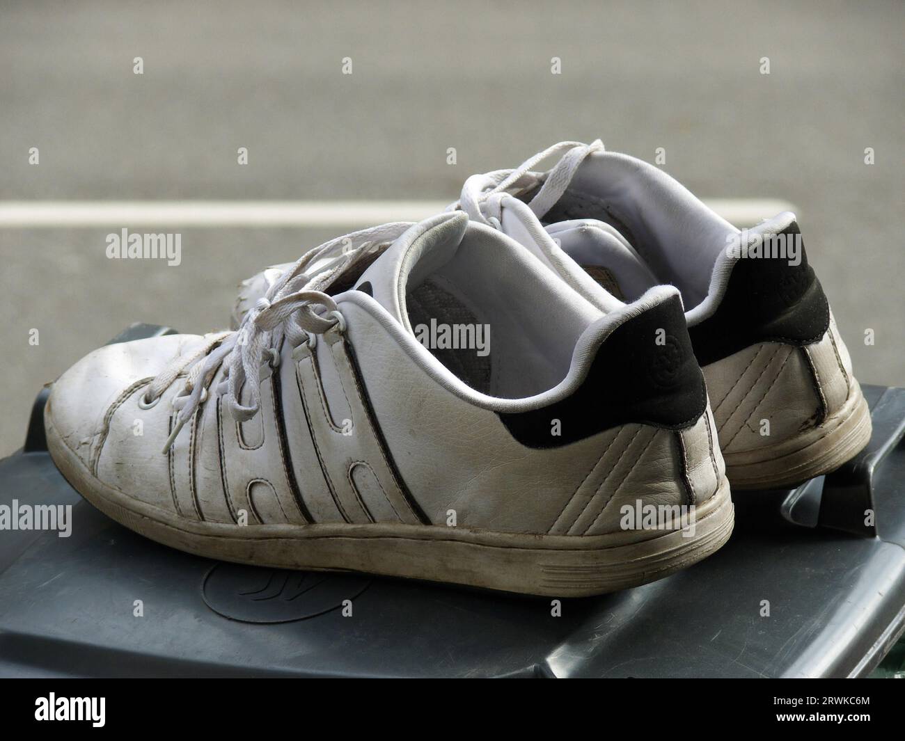 A pair of worn trainers, placed on a rubbish bin, background street in ...