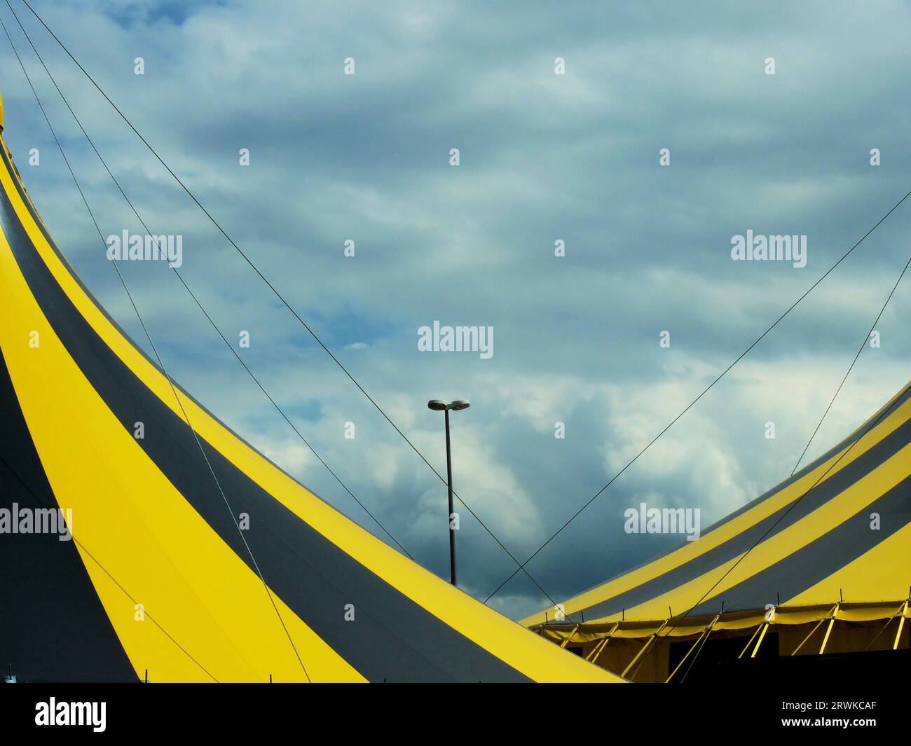 Two yellow and black circus tents, background street lamp and sky ...