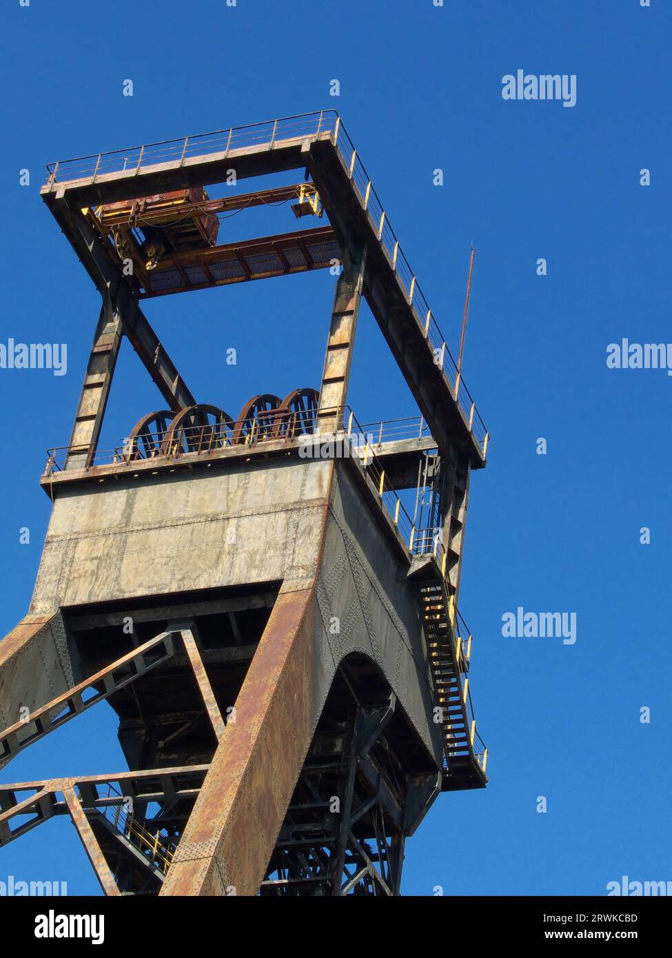 Disused winding tower of a mine with four winding wheels, blue sky in ...