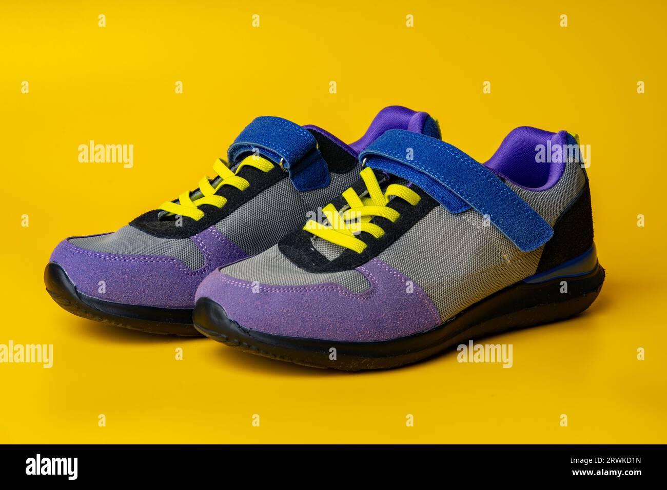 Violet-blue female sneakers on yellow studio background Stock Photo - Alamy