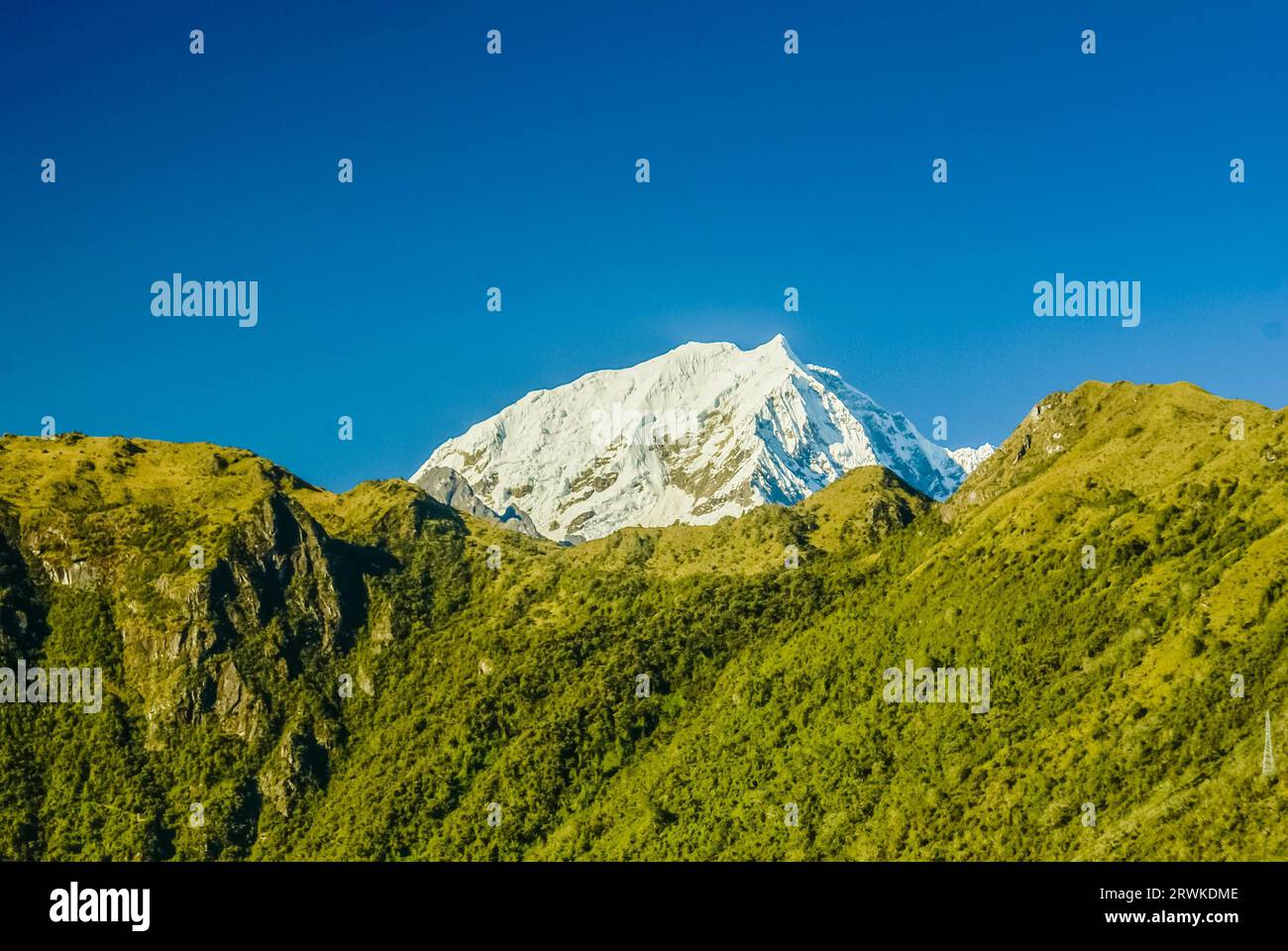 Mountainous region with greenery and snow-capped peaks in distance near ...