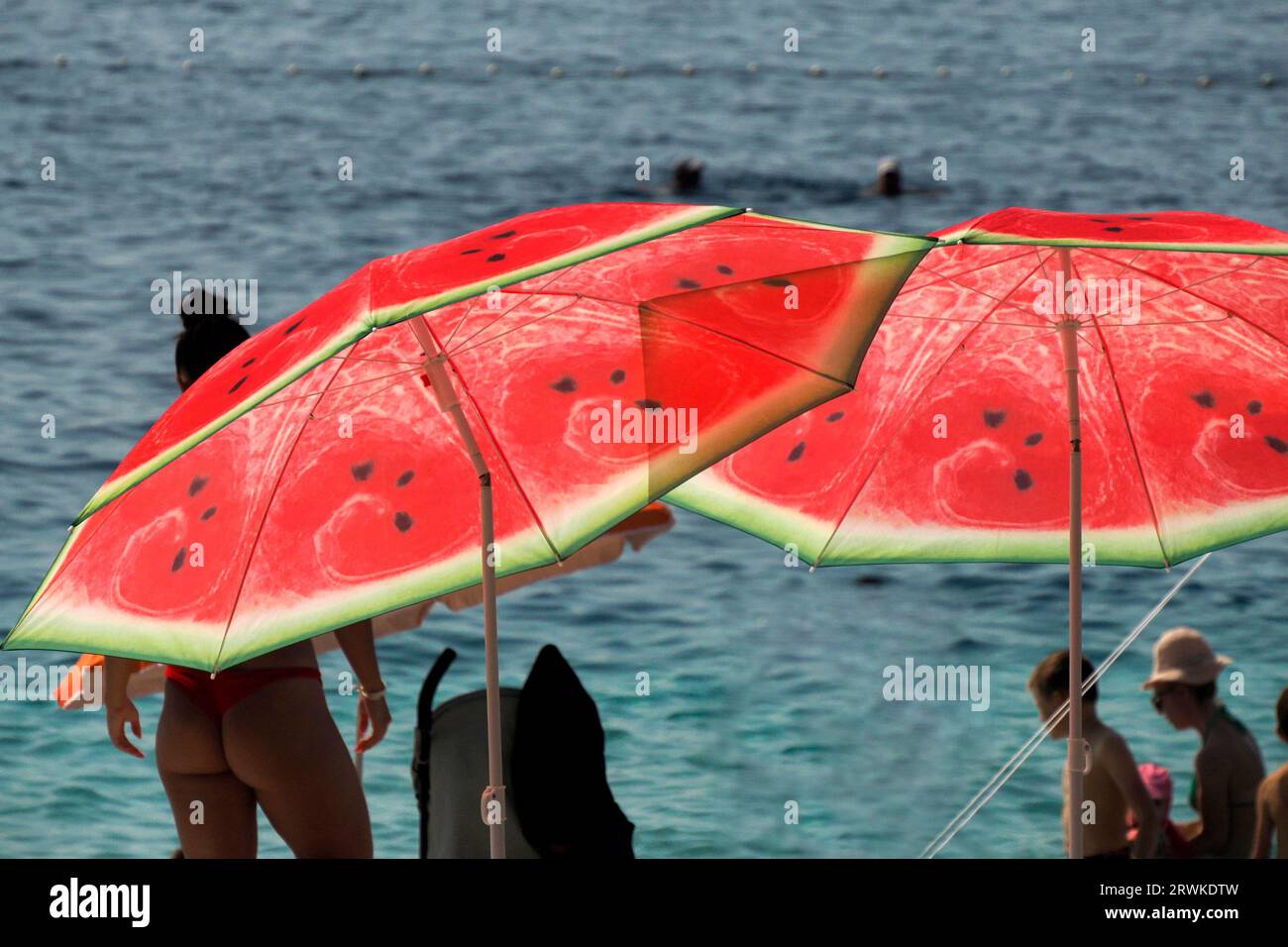Watermelon sun umbrella on the beach ofcrystal clear water of Adriatic ...