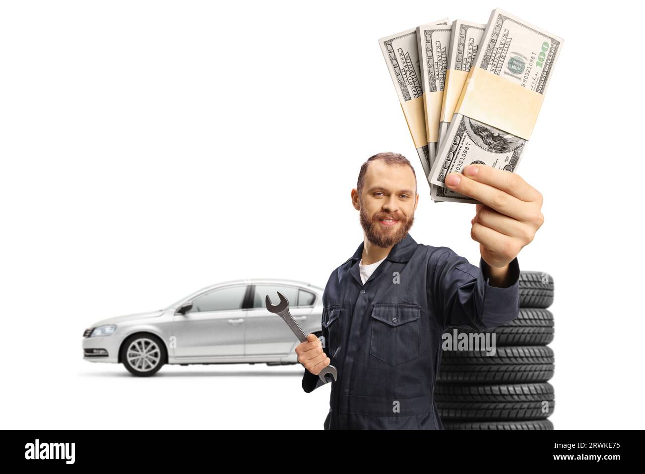 Mechanic with car tires in front of a car holding a wrench and showing ...