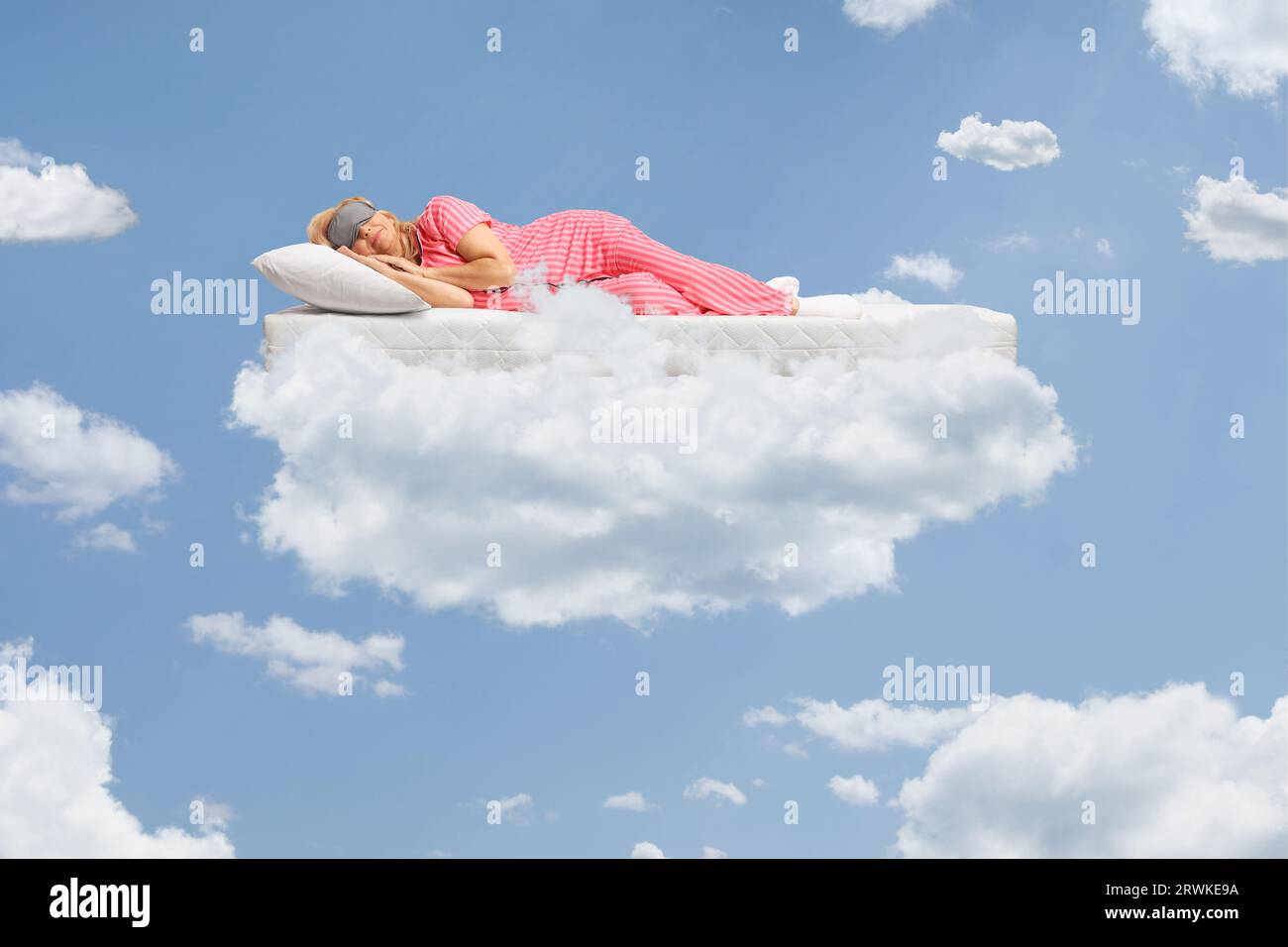Woman in pajamas sleeping on a mattress and floating on a cloud up in ...