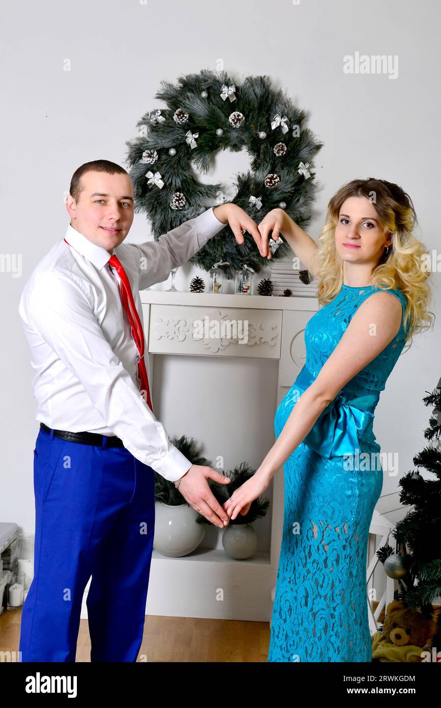 Attractive young couple is celebrating holiday at home. Standing on the ...