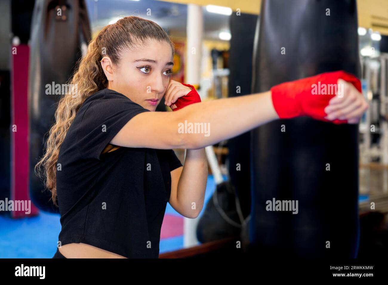 Female boxer training and hitting a punching boxing bag. Fighting sport ...