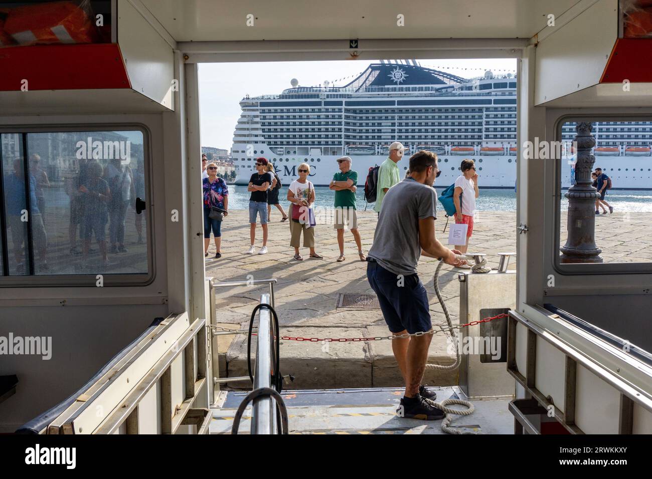 People waiting on dock in Trieste with cruise ship in background Stock Photo - Alamy