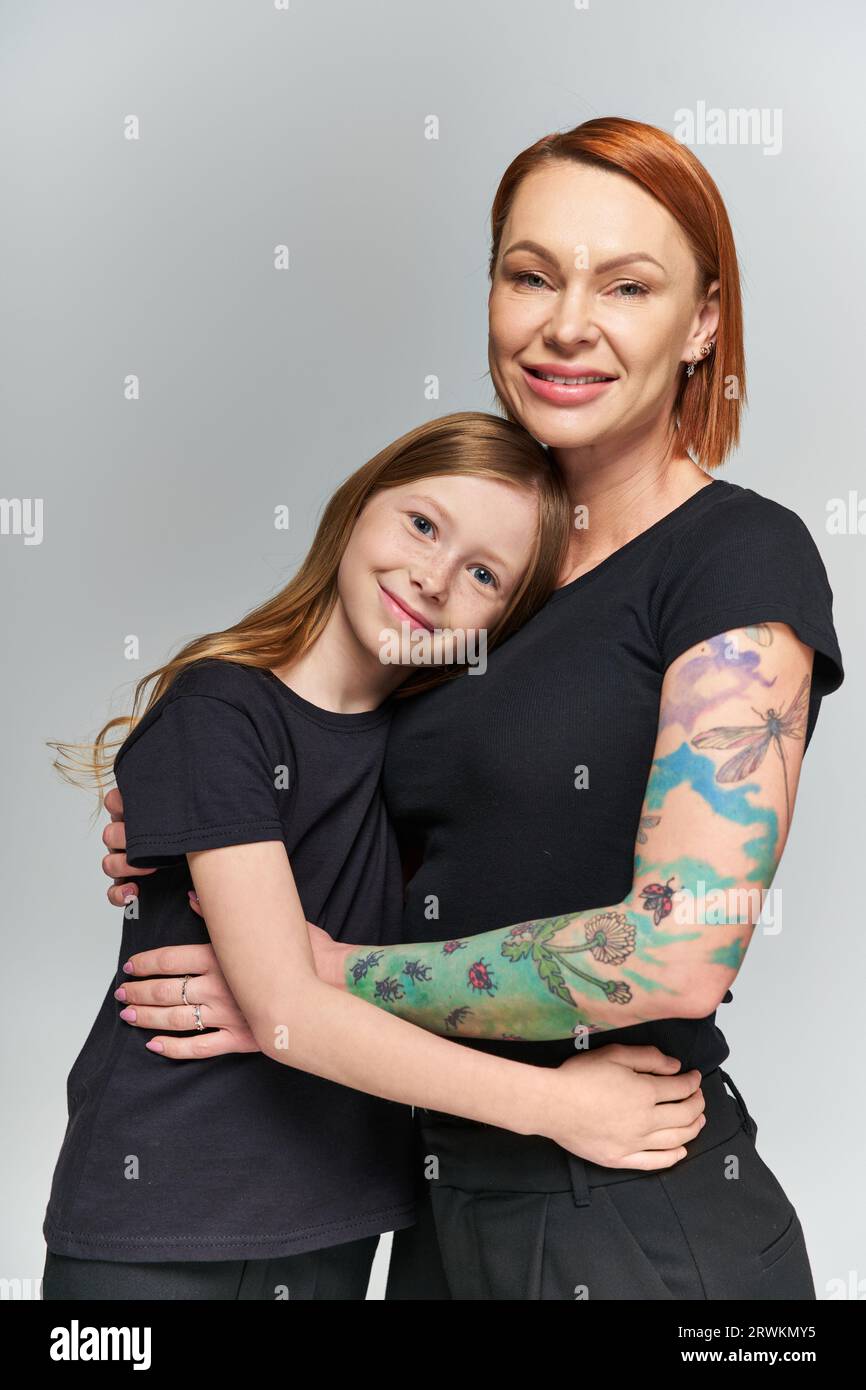 two generations, redhead woman and girl in matching attire hugging on ...