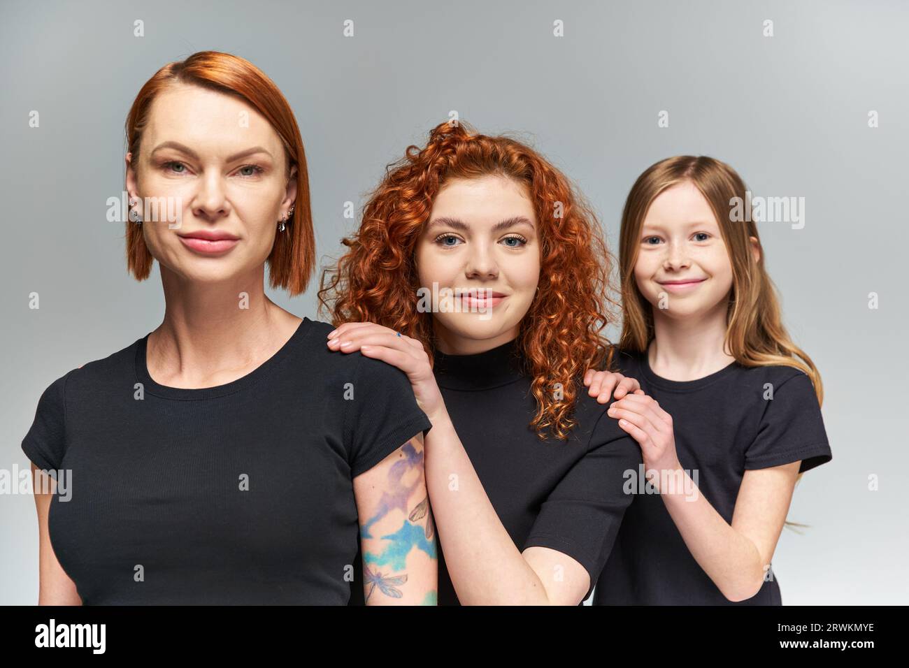 three generations of cheerful women and girl posing in matching outfits ...