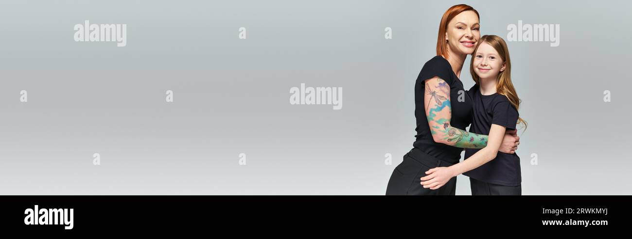 two generations, redhead woman and girl in matching attire hugging on ...