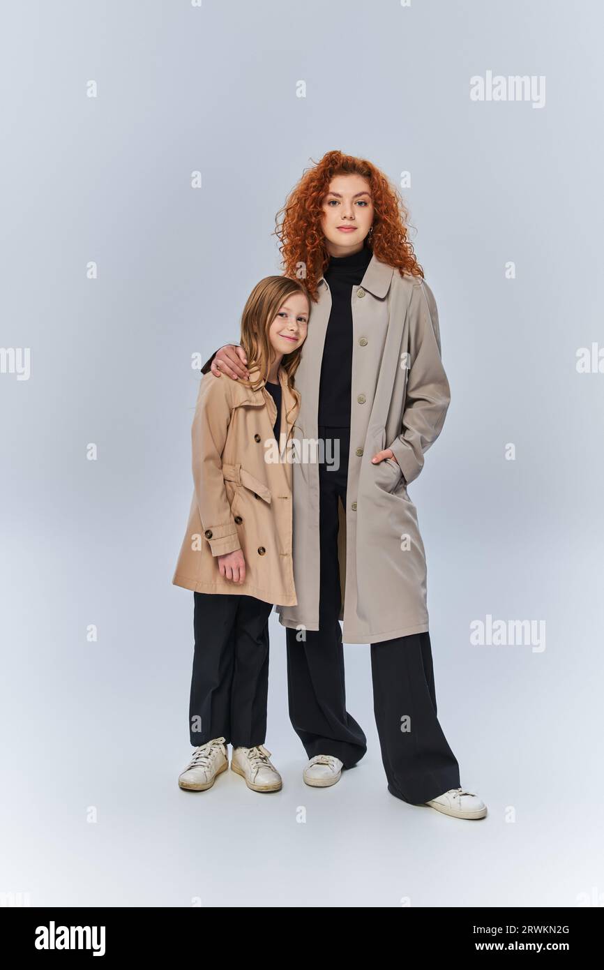 two female generations, redhead woman embracing happy kid and standing ...