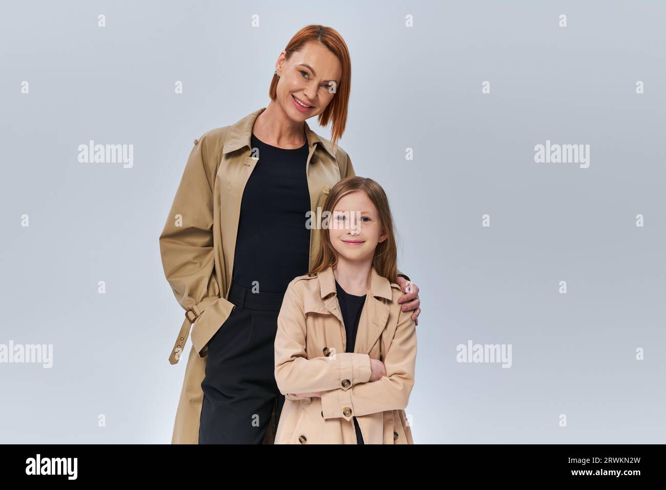 two generations, woman with red hair and little girl standing in trench ...