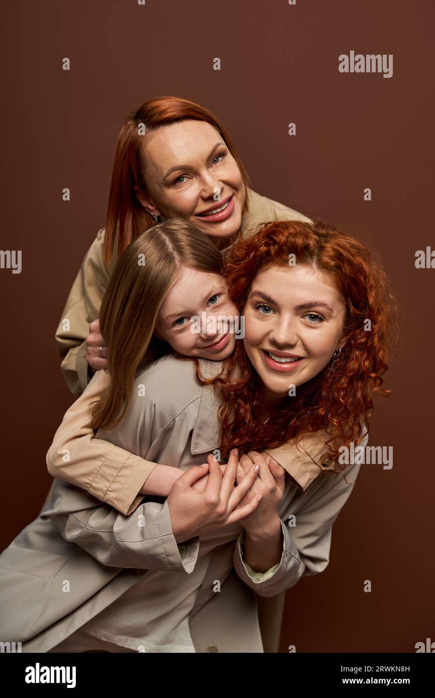 happy redhead family of three female generations in coats hugging each ...