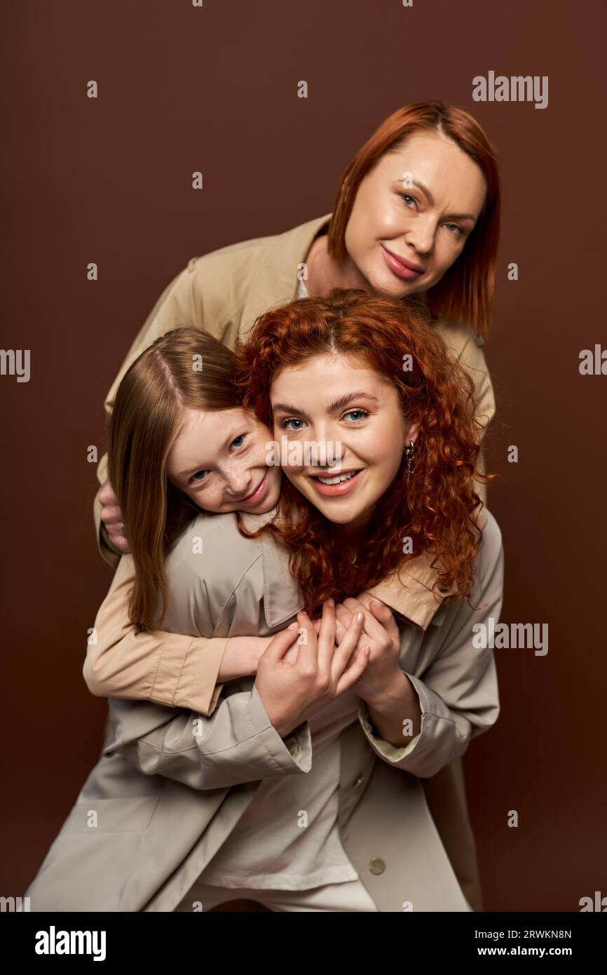 cheerful redhead family of three female generations in coats hugging ...