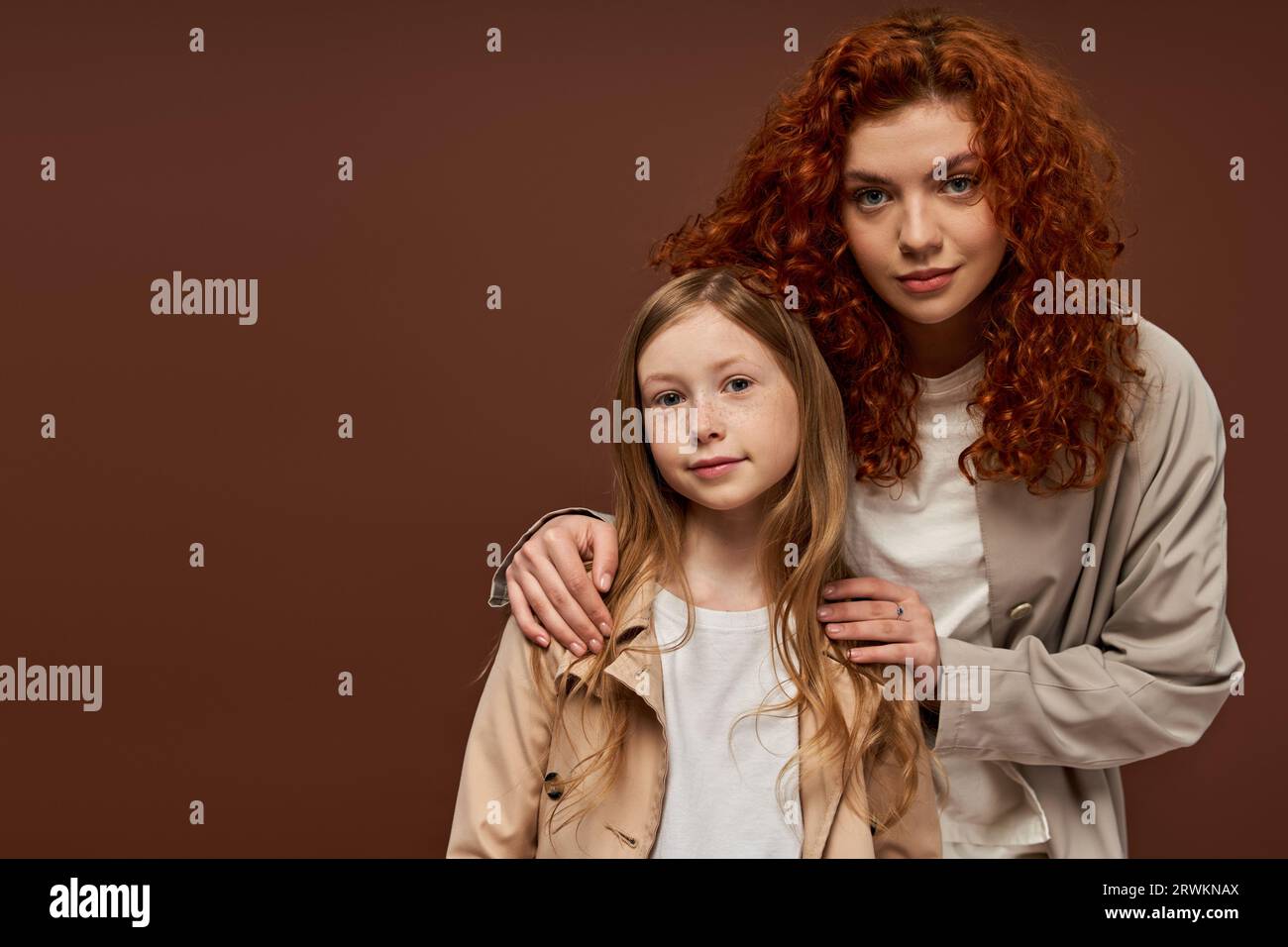 two generations, young curly mother with red hair looking at camera ...