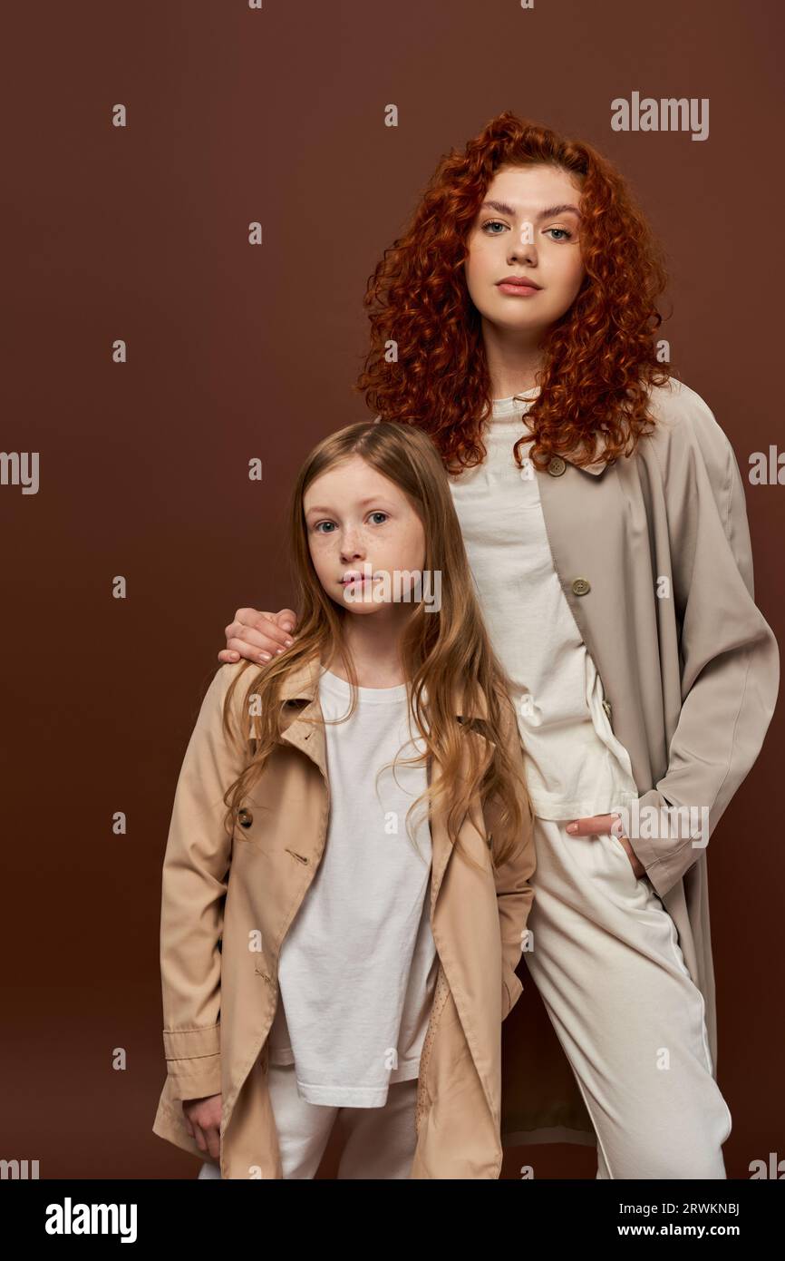 two generations, young curly mother looking at camera with redhead ...
