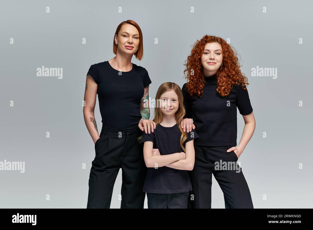 three generations of women in matching clothes standing on grey ...