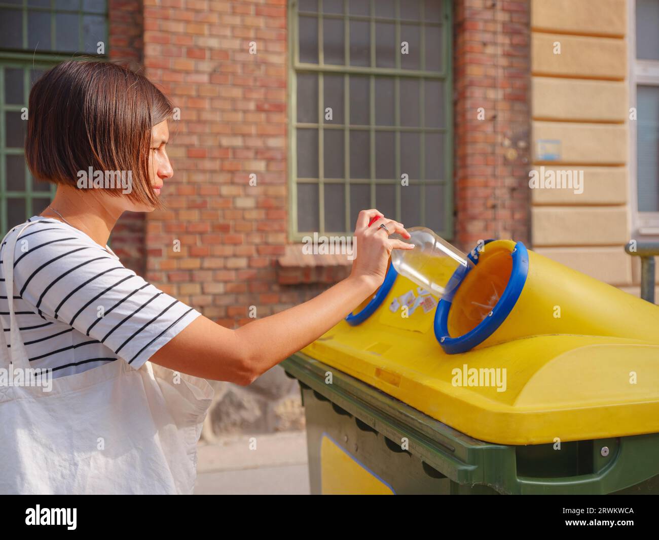 woman throwing plastic bottle Recycling bin stand on european street ...