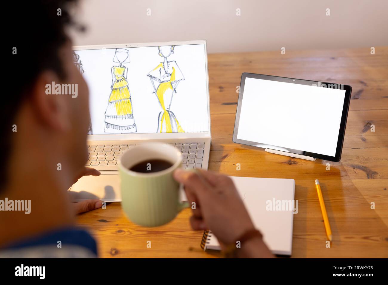 Focused biracial male fashion designer making video call in studio ...