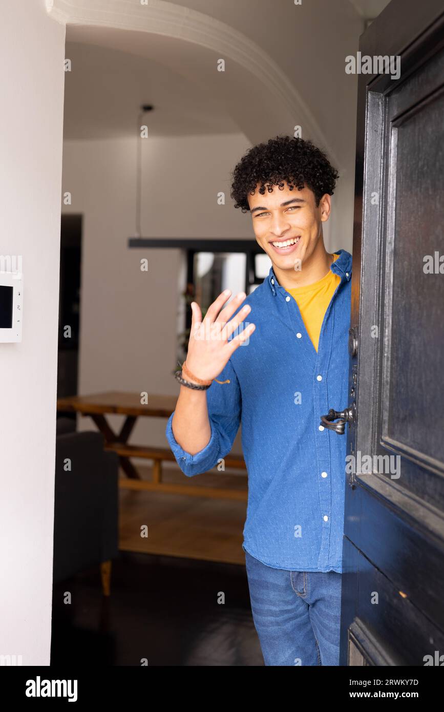 Happy biracial man standing, in doorway, smiling and waving Stock Photo ...