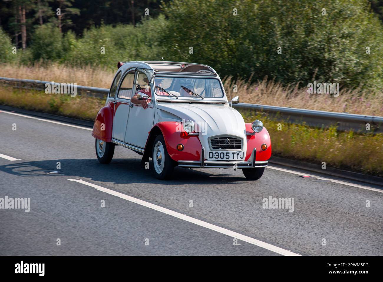 Senior couple driving a Citroen 2CV Dolly on a rural dual carriageway ...