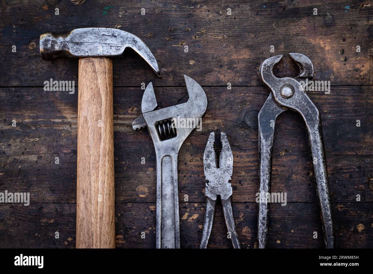 Old pliers, hammer, pincers and adjustable wrench on an old wooden ...