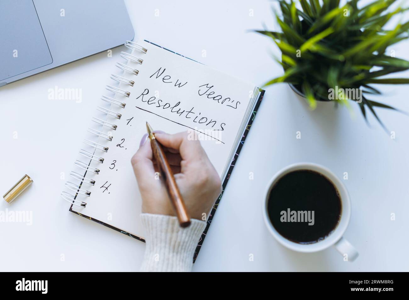 open notepad and woman hand writing new year resolutions. Flower ...